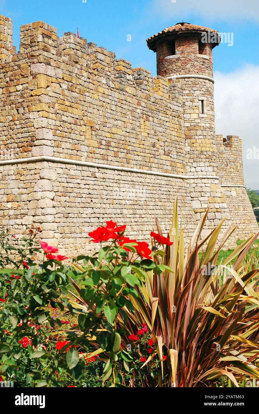 A garden blooms near a stone, fortress wall, a winery built to resemble ...