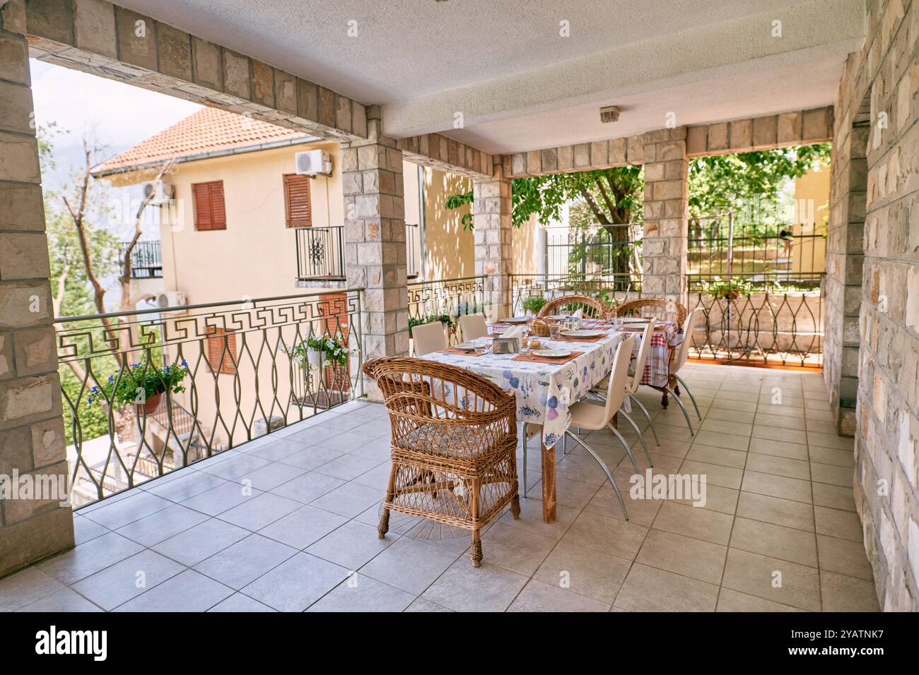 Laid table with wicker chairs stands on a terrace with columns of a ...