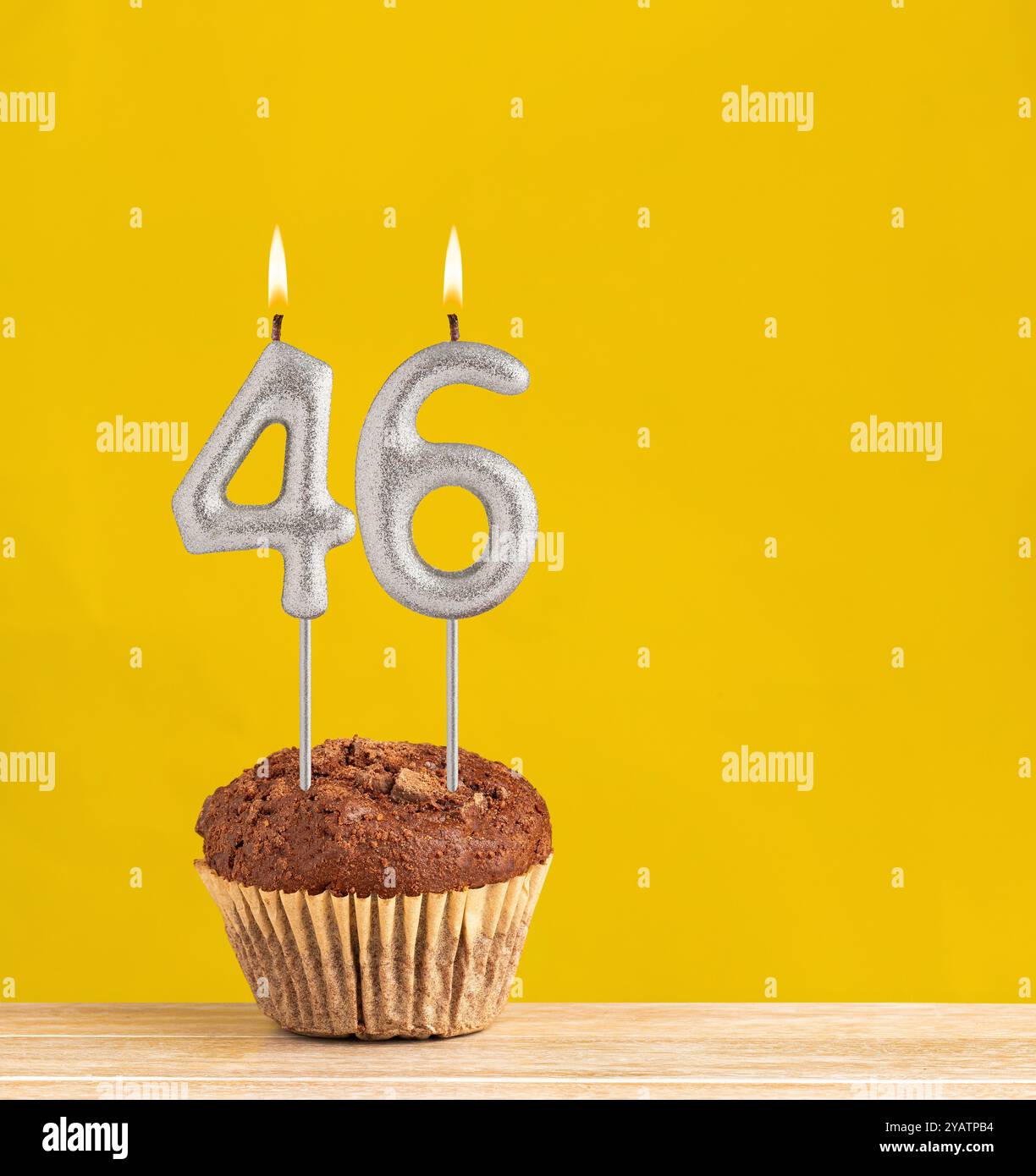 Chocolate cupcake with number 46 candle - Birthday on a yellow ...