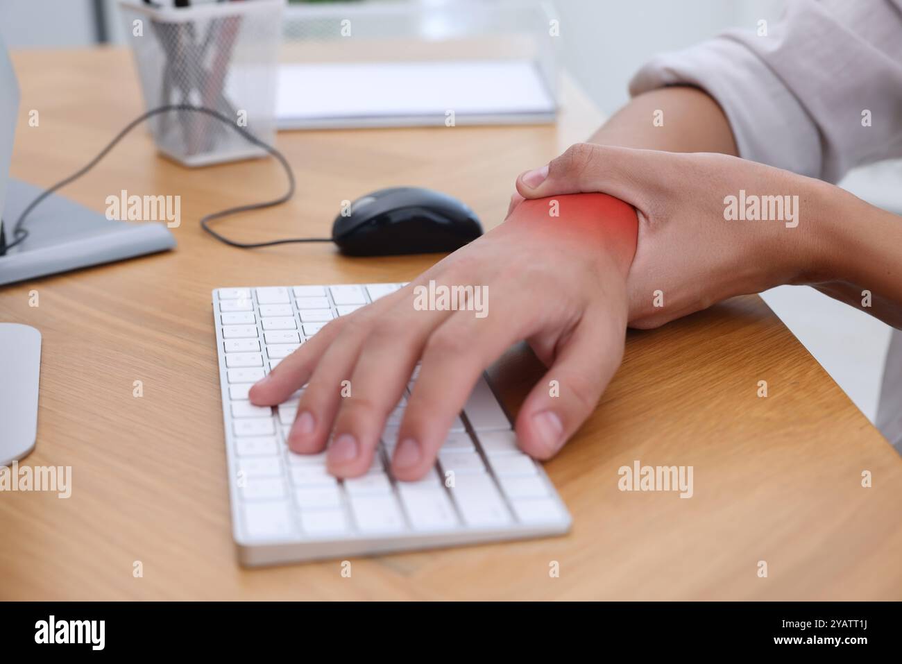 Man suffering from pain in wrist at wooden table, closeup. Office work ...