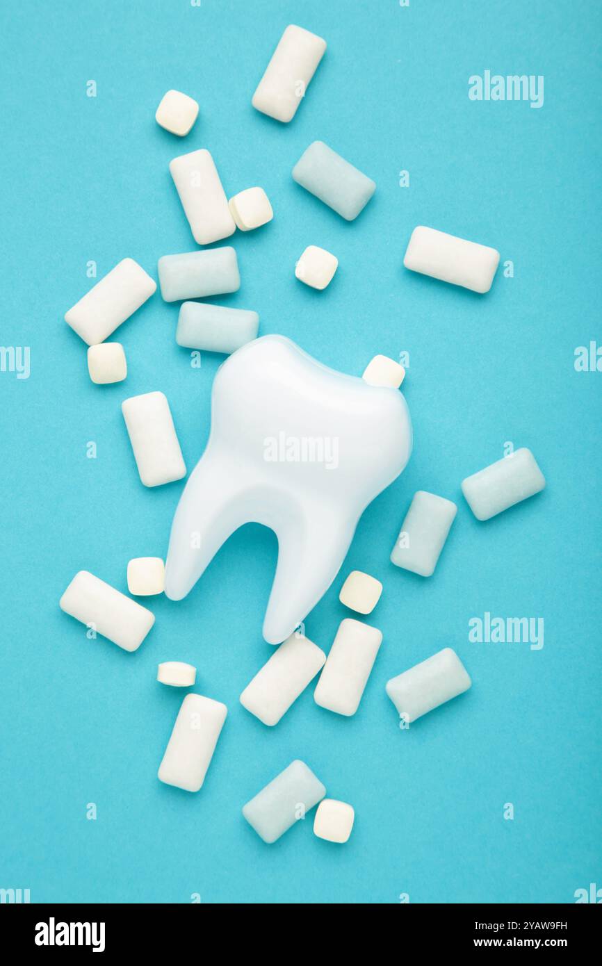 White healthy tooth model and heap of chewing gums on blue background ...