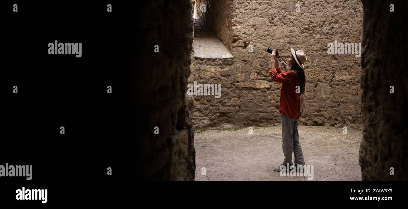 Woman tourist explores an ancient fortress, taking photographs with her ...