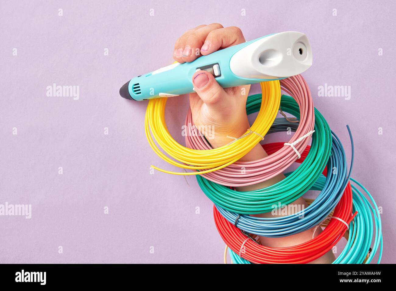 Kids hand holding a 3D printing pen with colorful filament rolls. 3D ...