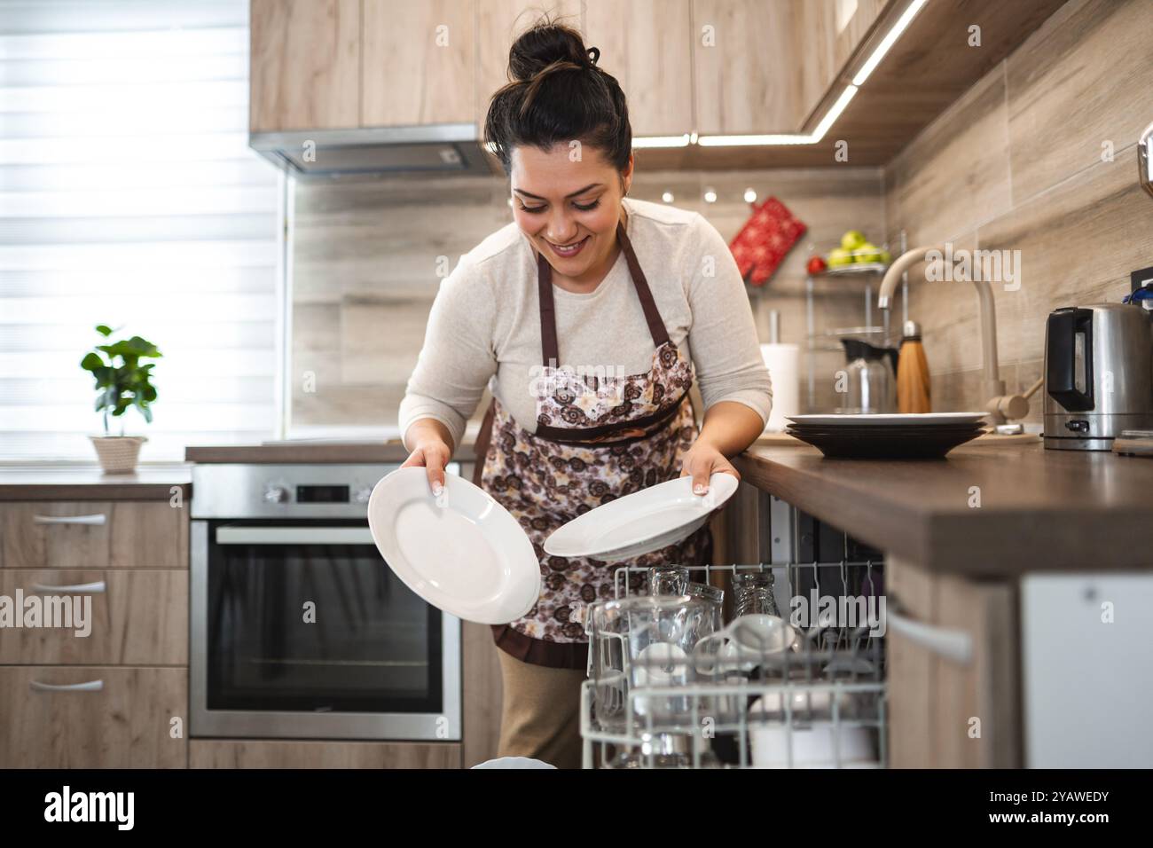 Woman loading the dishwasher in the kitchen Stock Photo - Alamy