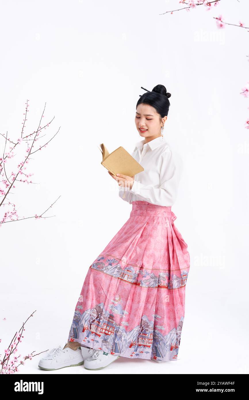 A young Chinese woman reading with a book in her hand Stock Photo - Alamy
