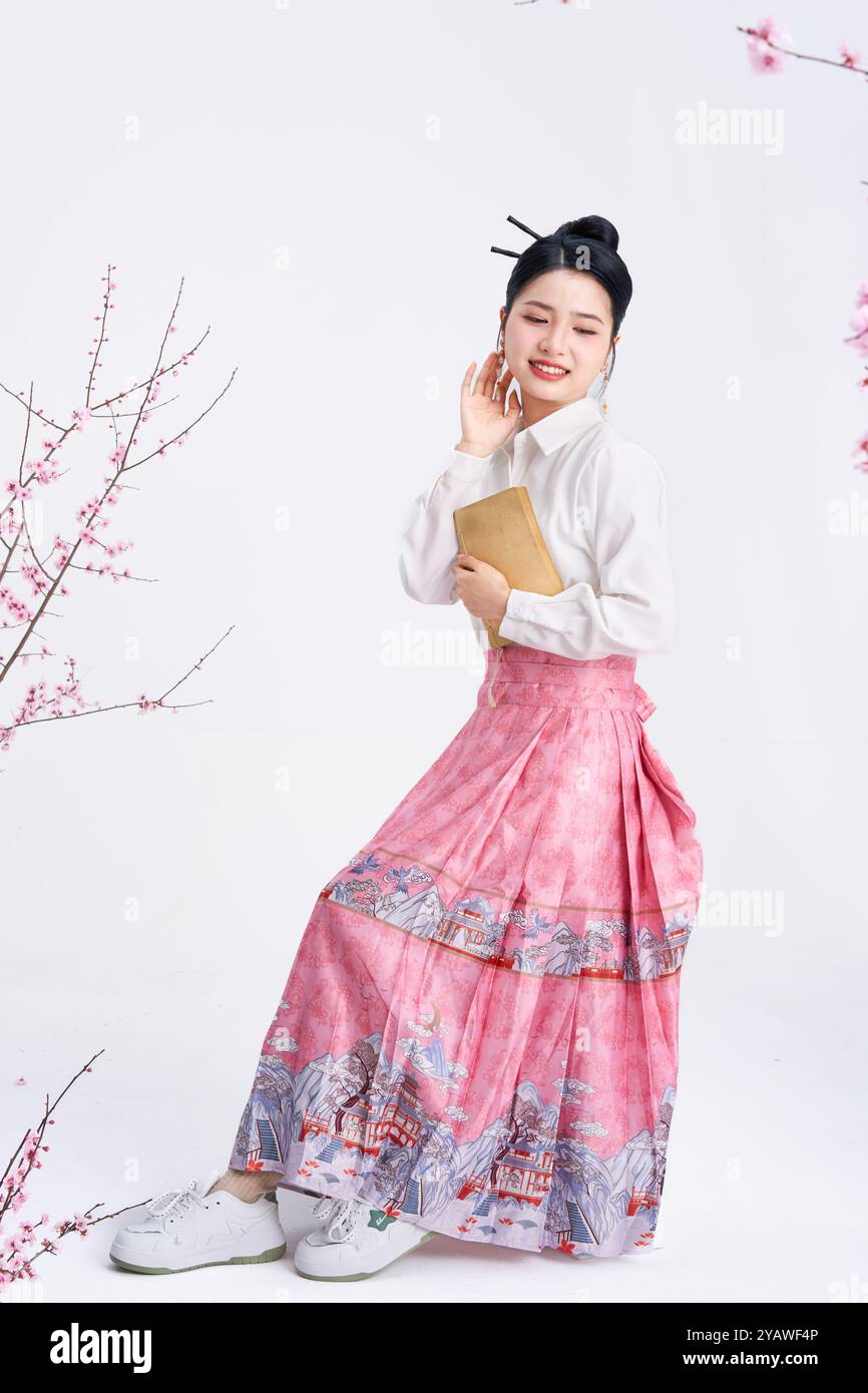 A young Chinese woman reading with a book in her hand Stock Photo - Alamy