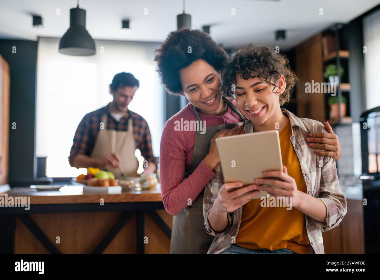 Happy multiethnic parents and kid having fun while cooking and ...