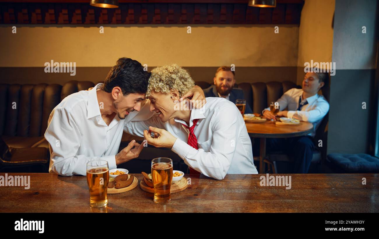 Two colleagues share heartfelt laugh at modern bar, leaning in close ...