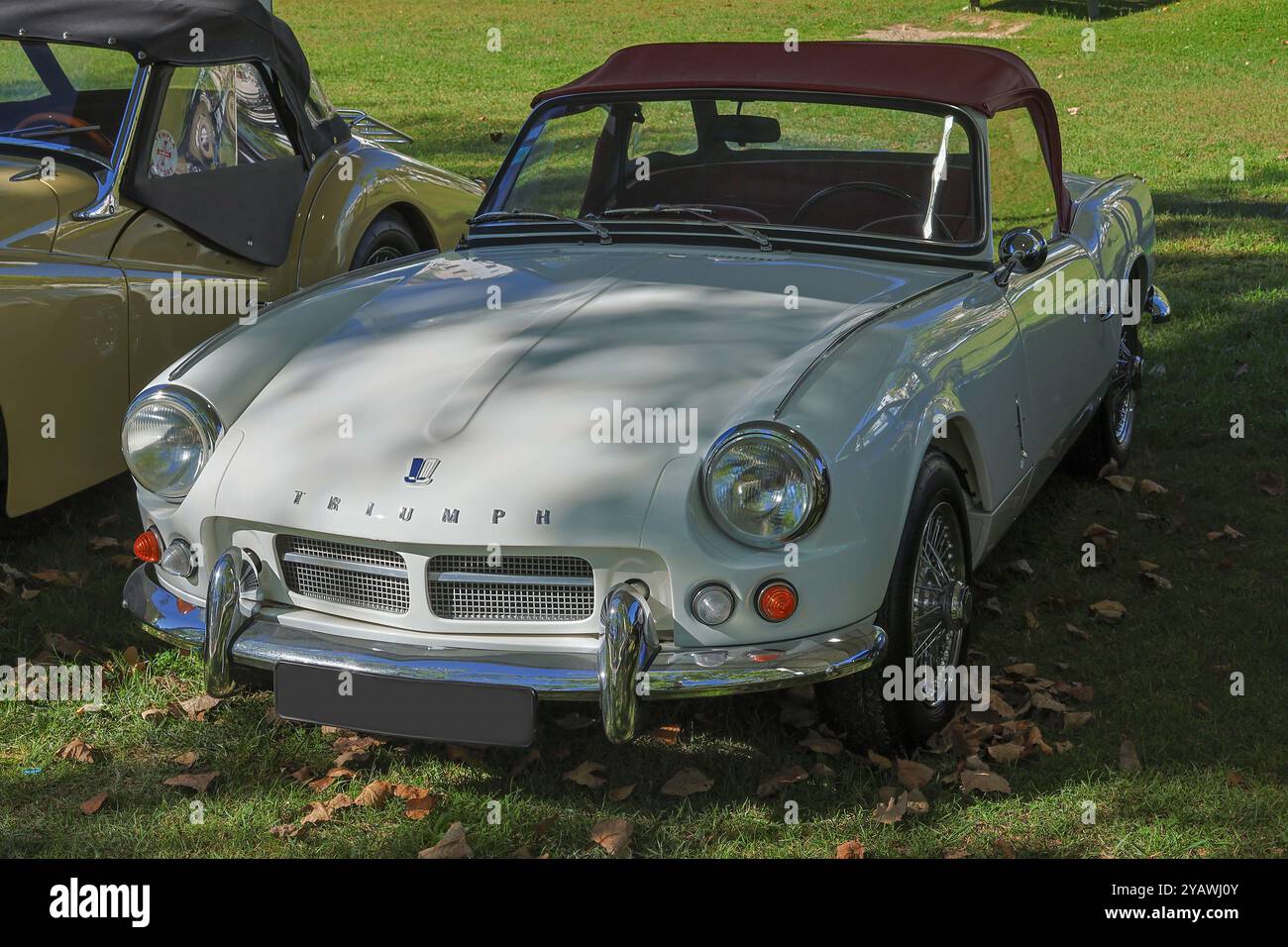 White triumph spitfire with its top down parked on grass at a car show ...