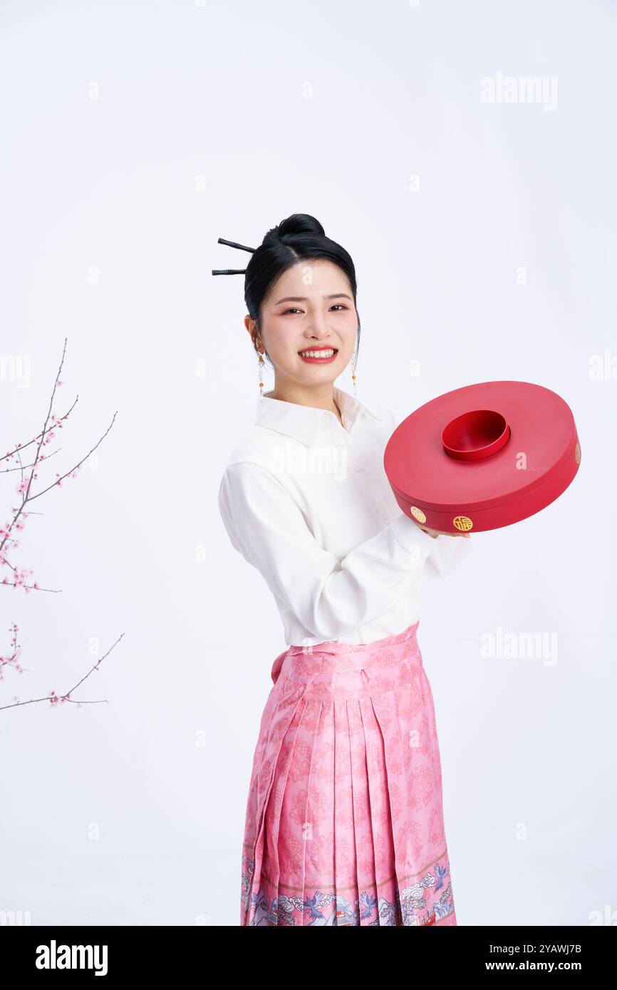 A young Chinese girl wearing a traditional long dress and holding a ...