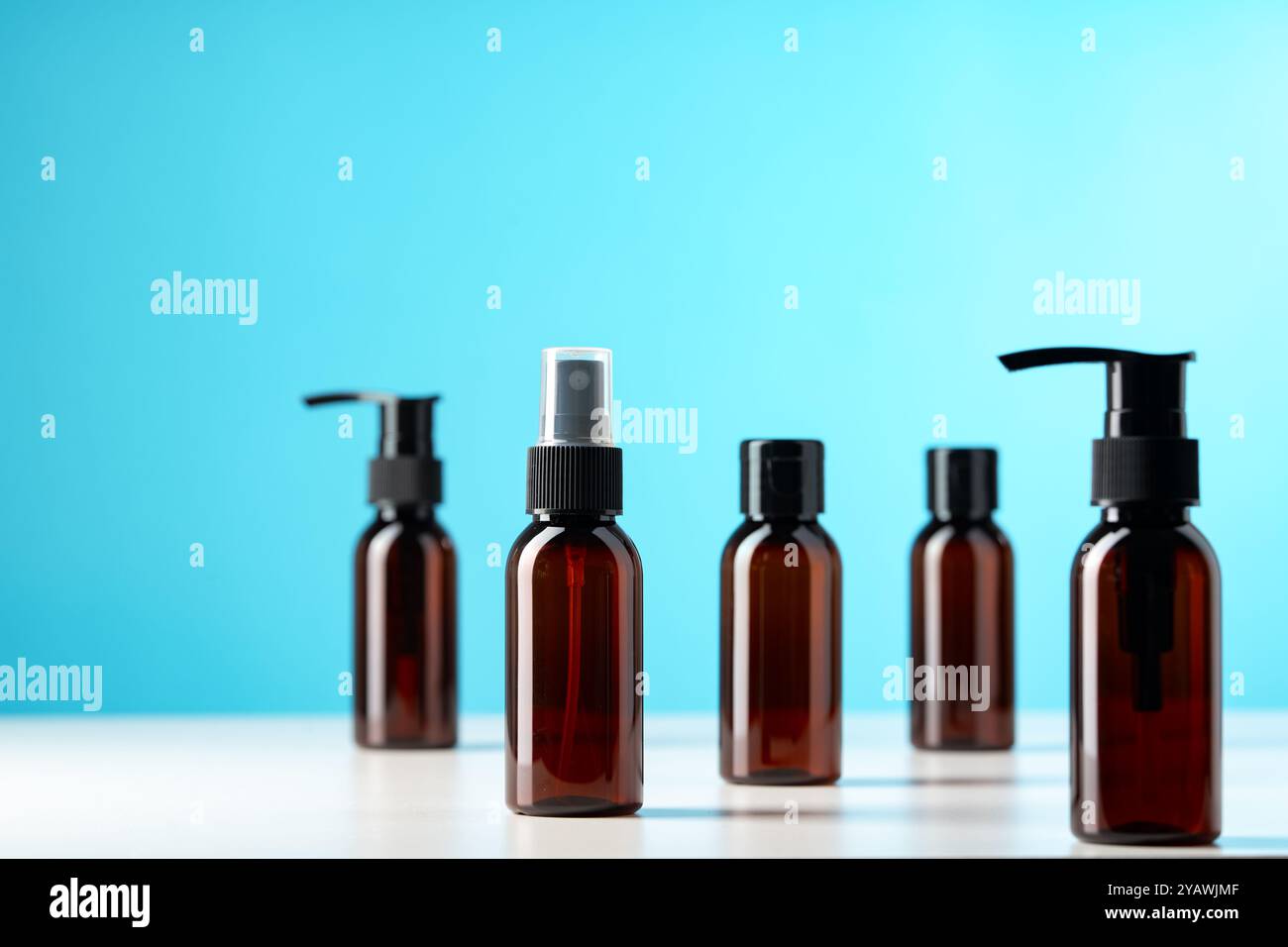 Collection of amber glass bottles with pumps and spray tops on a light ...