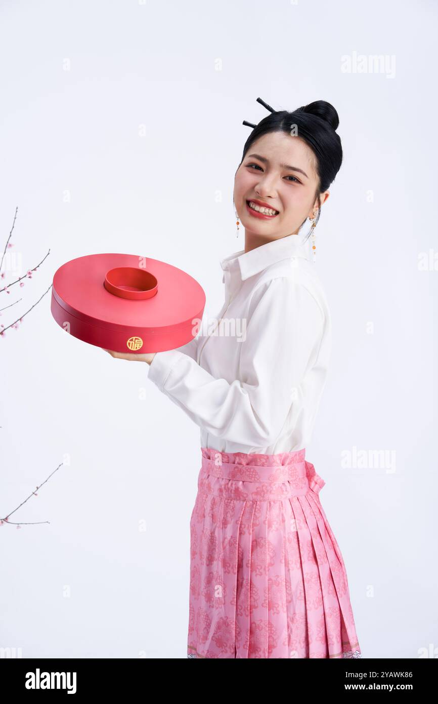 A young Chinese girl wearing a traditional long dress and holding a ...