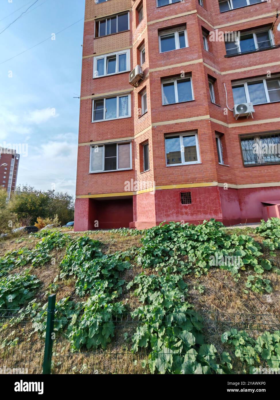 A tall red and beige brick residential building with multiple balconies ...