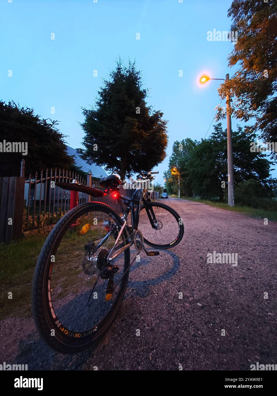 "Mountain bike resting on a quiet suburban street at dusk, illuminated ...