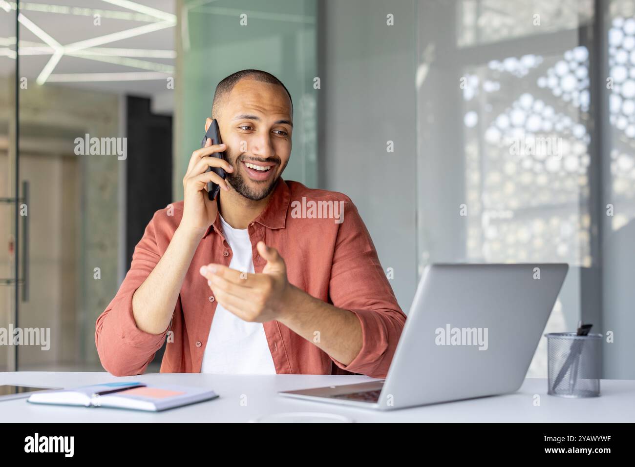 Confident business professional engaged in phone call using laptop in ...