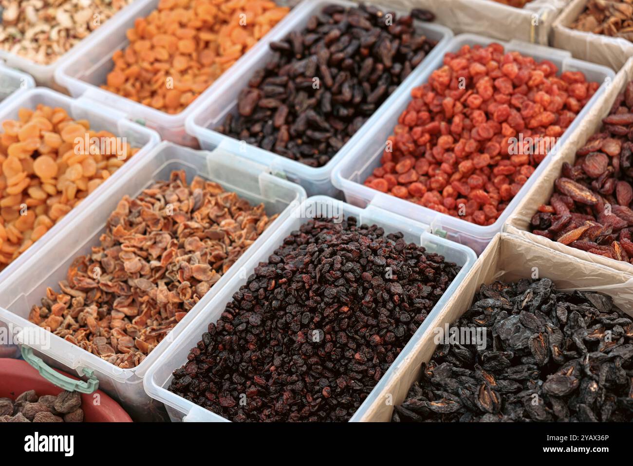 A vibrant array of dried fruits and nuts is arranged in clear ...