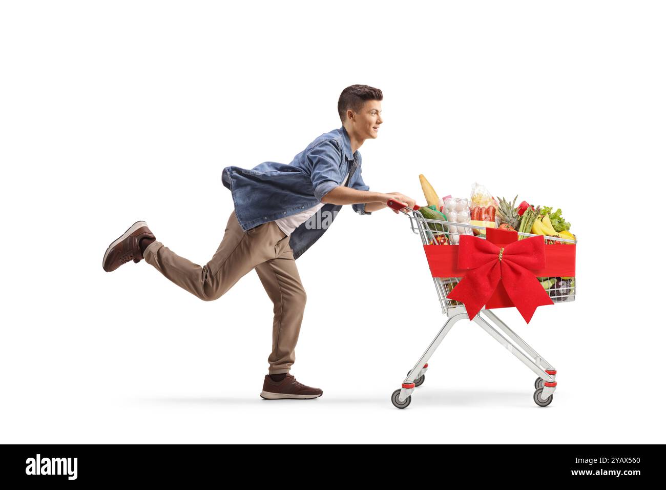 Young man running with groceries in a shopping cart isolated on white ...