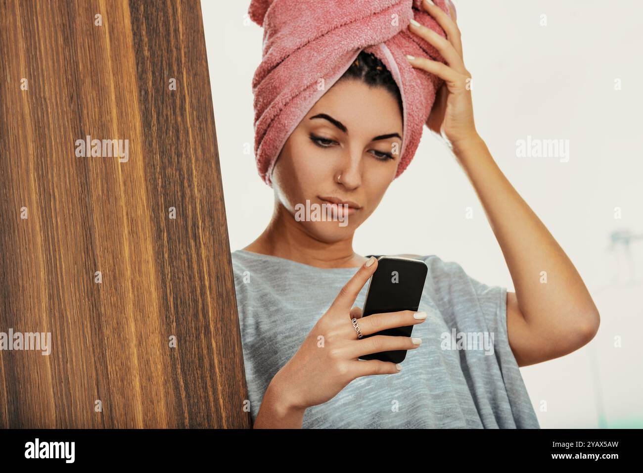 Young woman multitasks at home, holding her smartphone, reading news ...