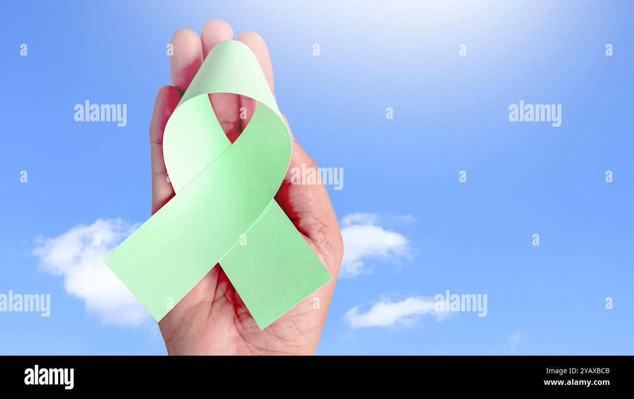 Hand holding green ribbon, symbolizing ovarain cancer awareness. Ribbon ...