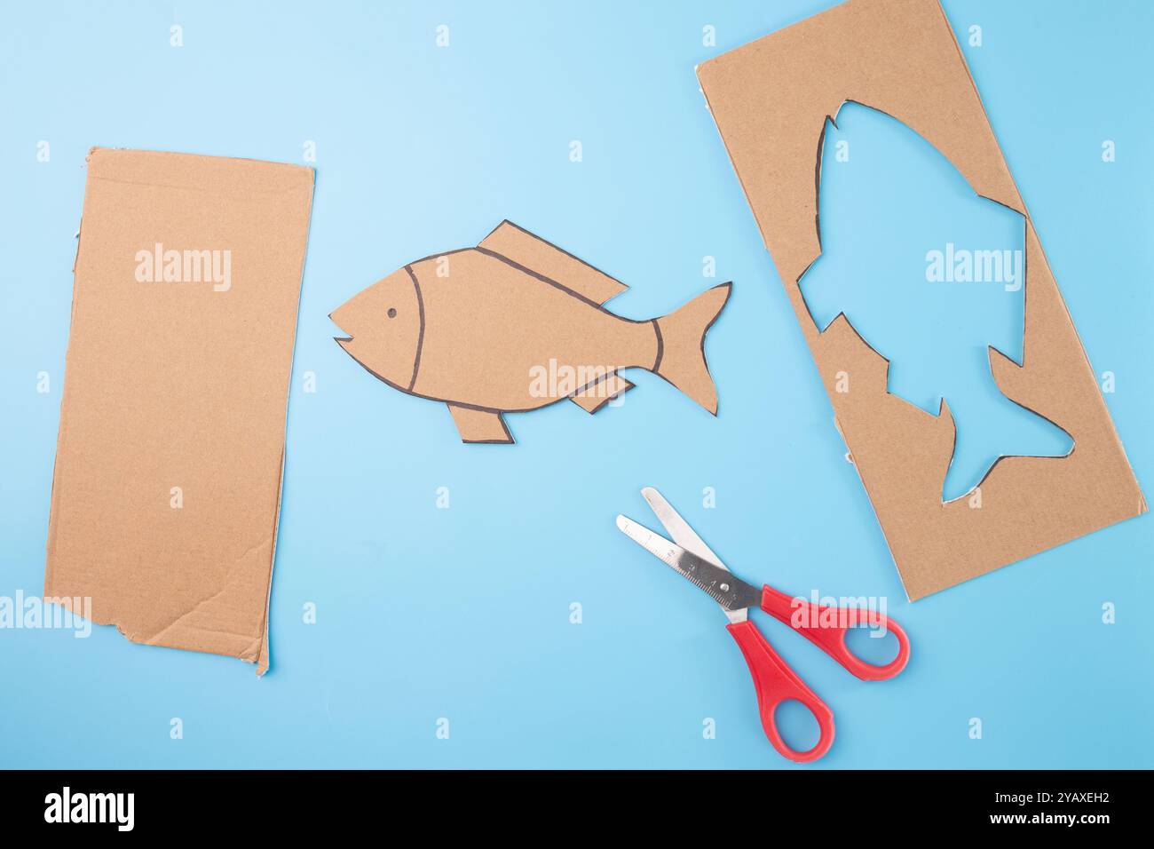 cardboard cut into the shape of a fish, blue background, top view, step ...