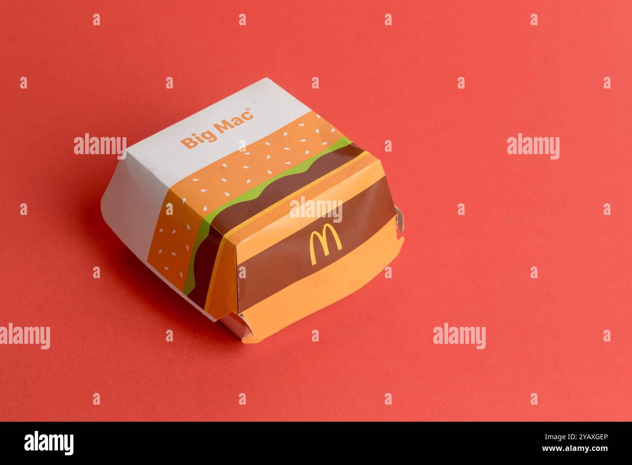 London, United Kingdom, 14th October 2024:- A view of a McDonalds Big Mac box, against a red ...