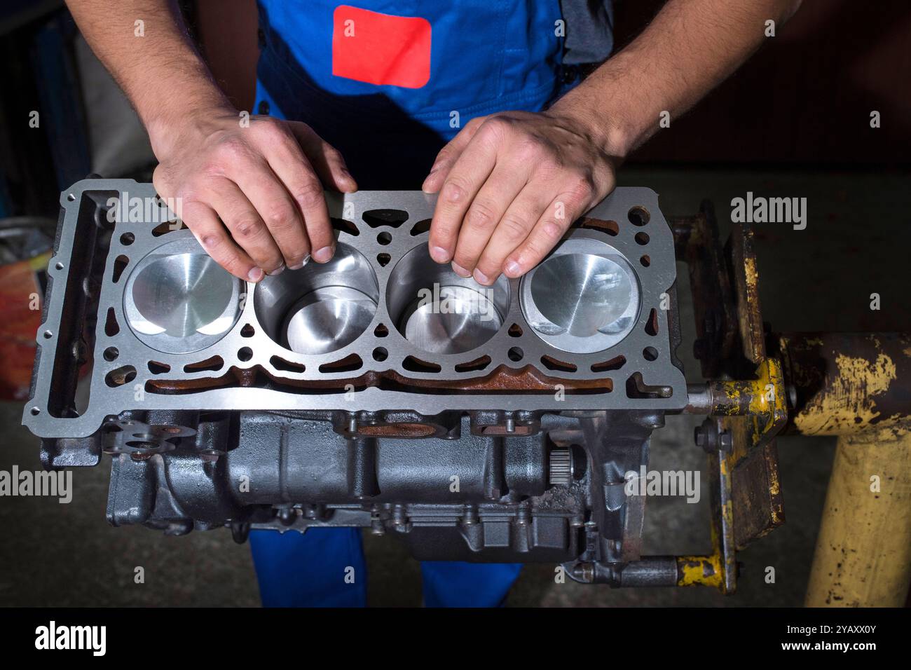 An auto mechanic installs a cylinder block in a car engine Stock Photo ...