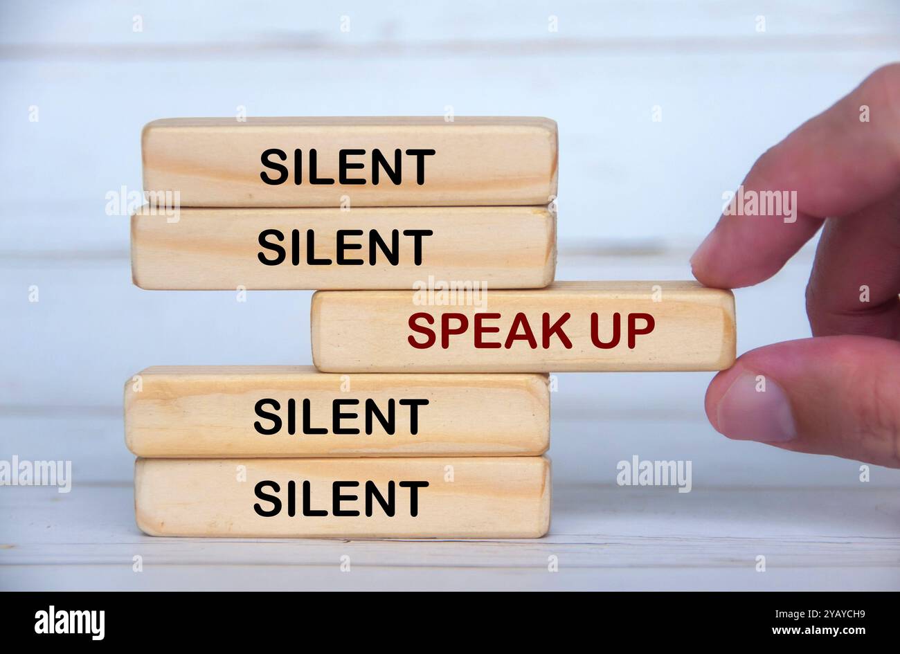 Speak up and silent text on wooden block with hand pulling the wooden ...