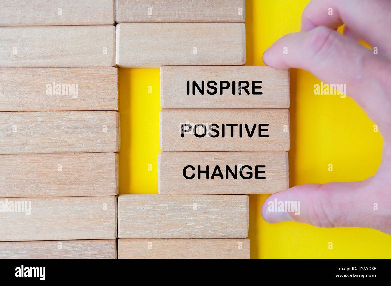 Hand pulling out wooden blocks with Inspire Positive Change text Stock ...