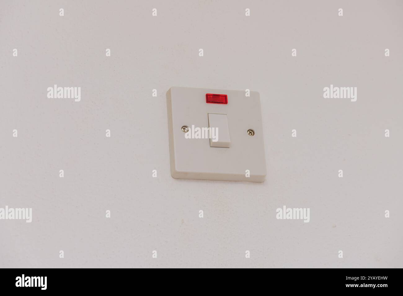 Illuminated by the ambient light, a sleek white light switch stands ...