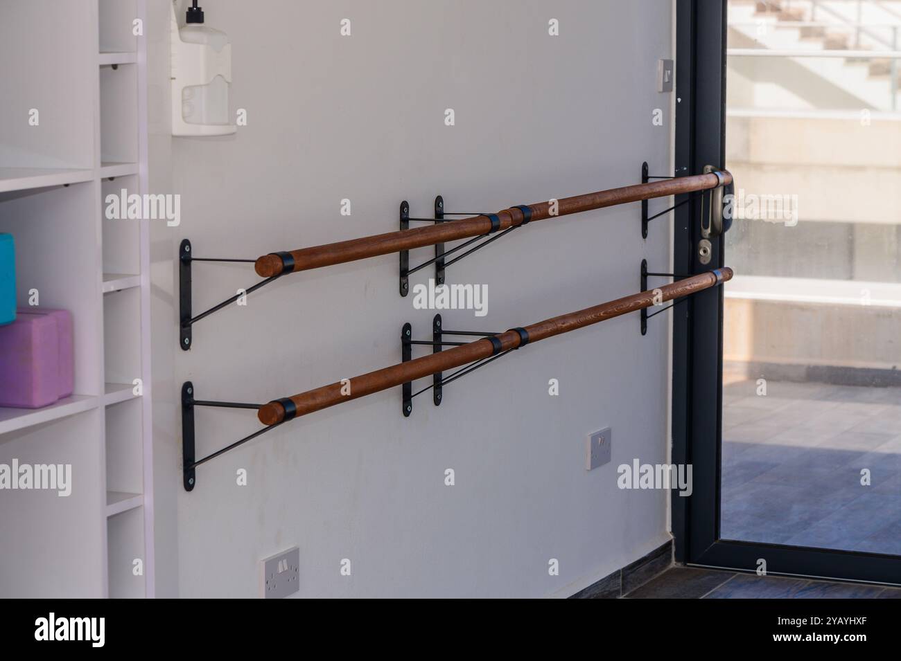 A beautifully crafted wooden barre is securely mounted on a ...