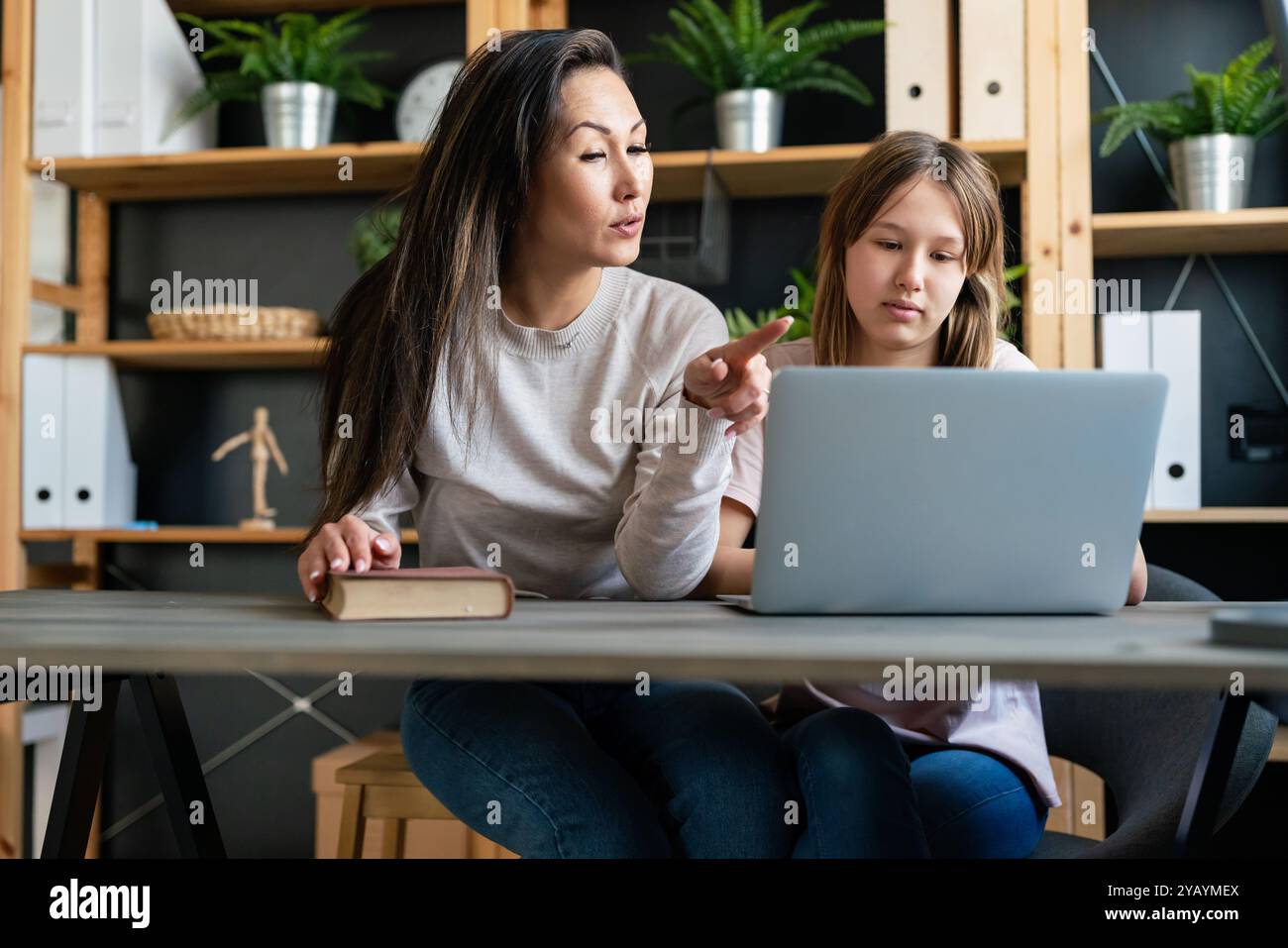 Happy young asian single mother studying with teenage child girl using ...