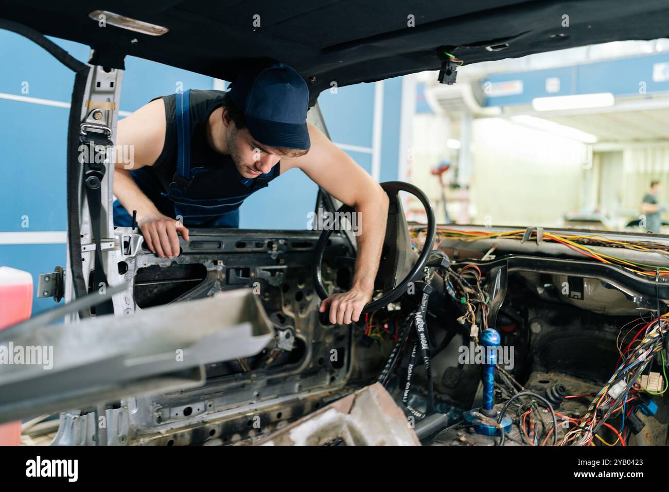 View from interior of old vehicle to skilled mechanic in blue overalls ...