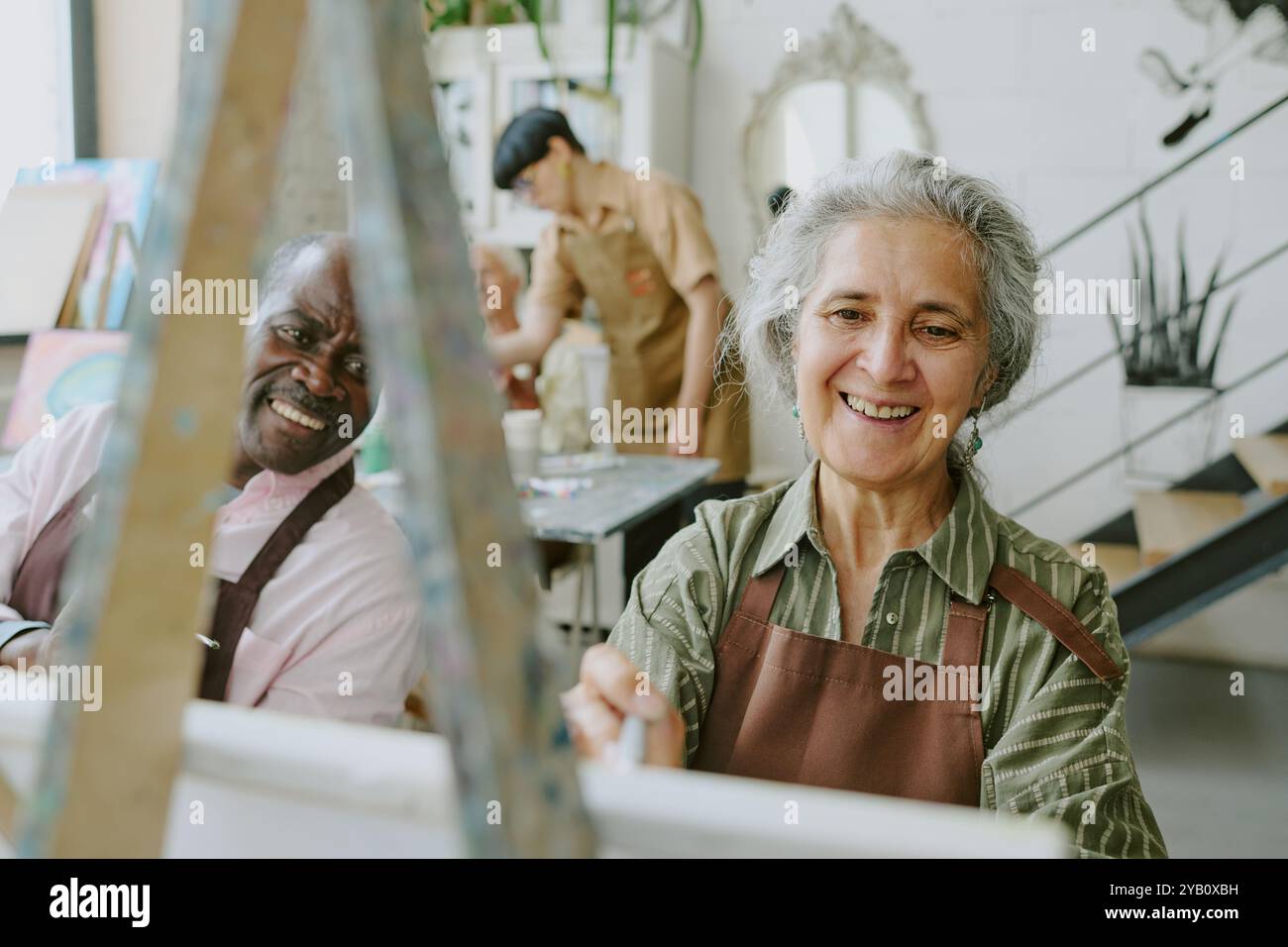 Silver haired woman smiling widely while enjoying drawing process, her ...