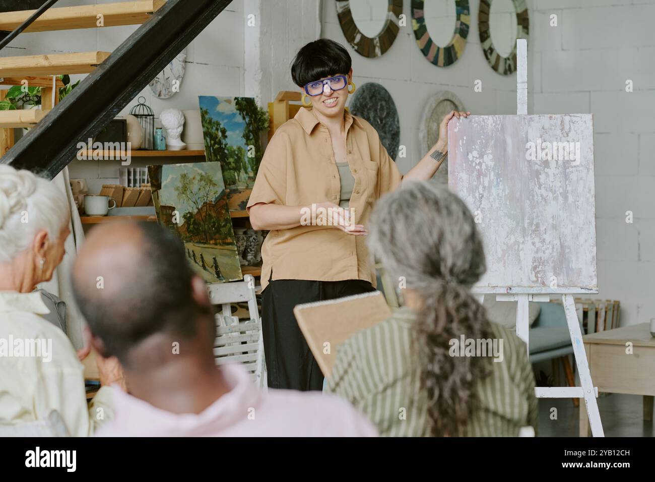 Back view shot of senior biracial group of people listening to young female teacher who ...