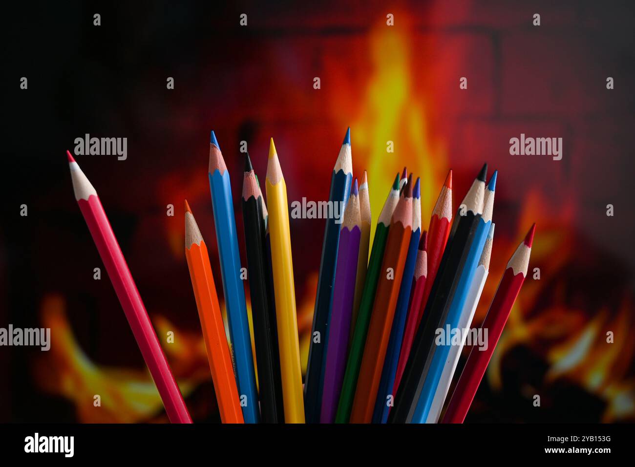 Bunch of colored pencils standing upright against a fiery background ...