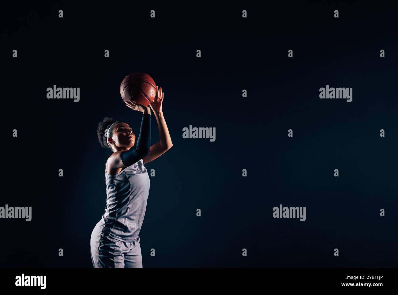 Professional female basketball player throwing basketball against black ...