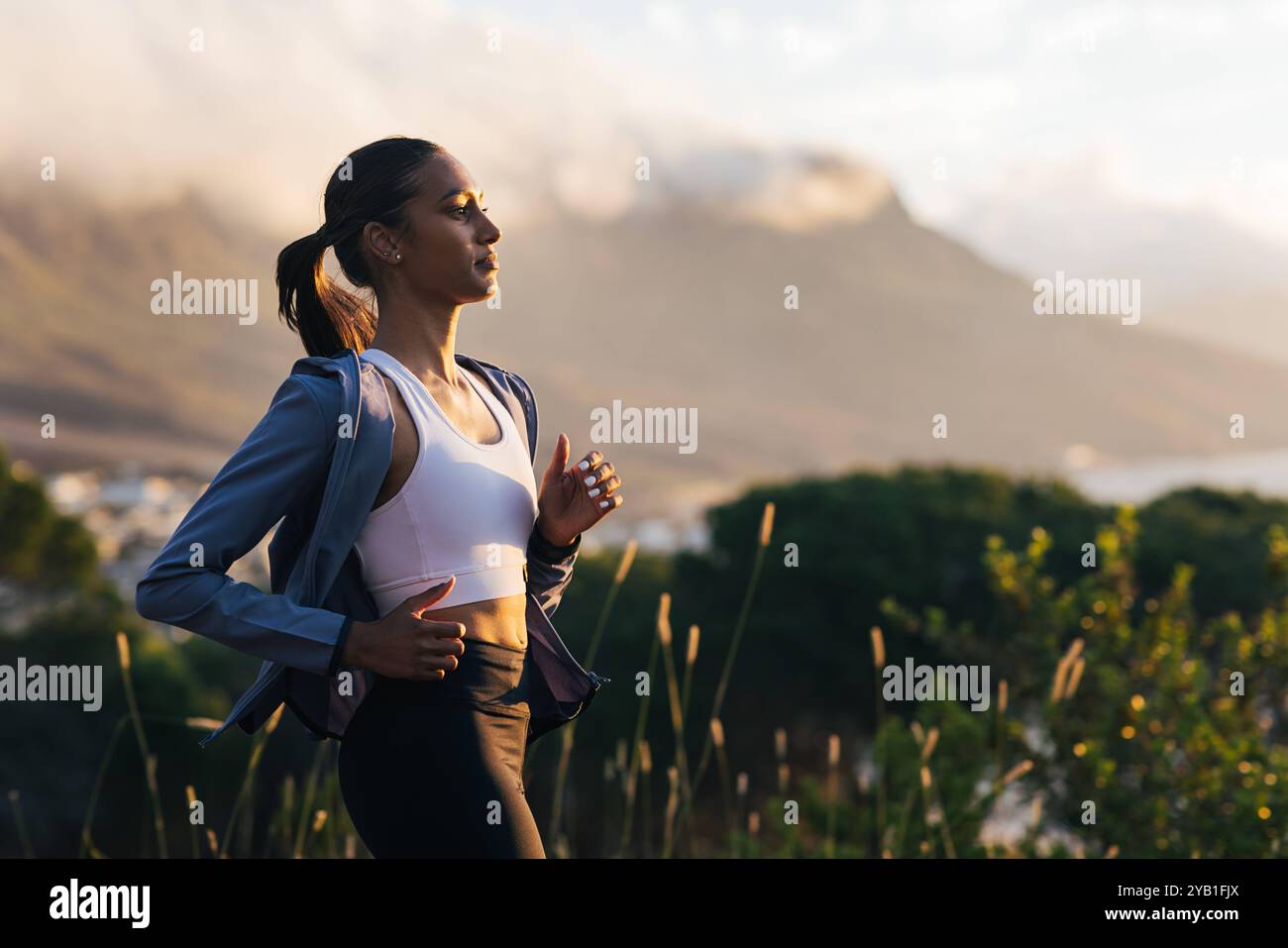 Side view of a young slim female jogging outdoors at a stunning sunset ...