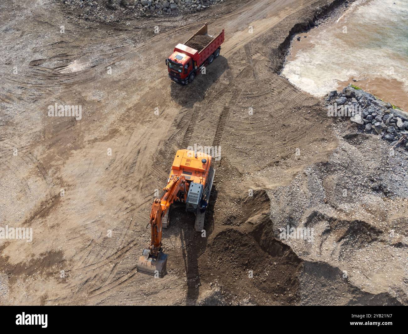 Aerial view of an excavator loading sand into a truck, top view ...