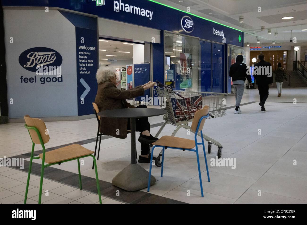 An elderly lady sits inside a London shopping centre holding her ...