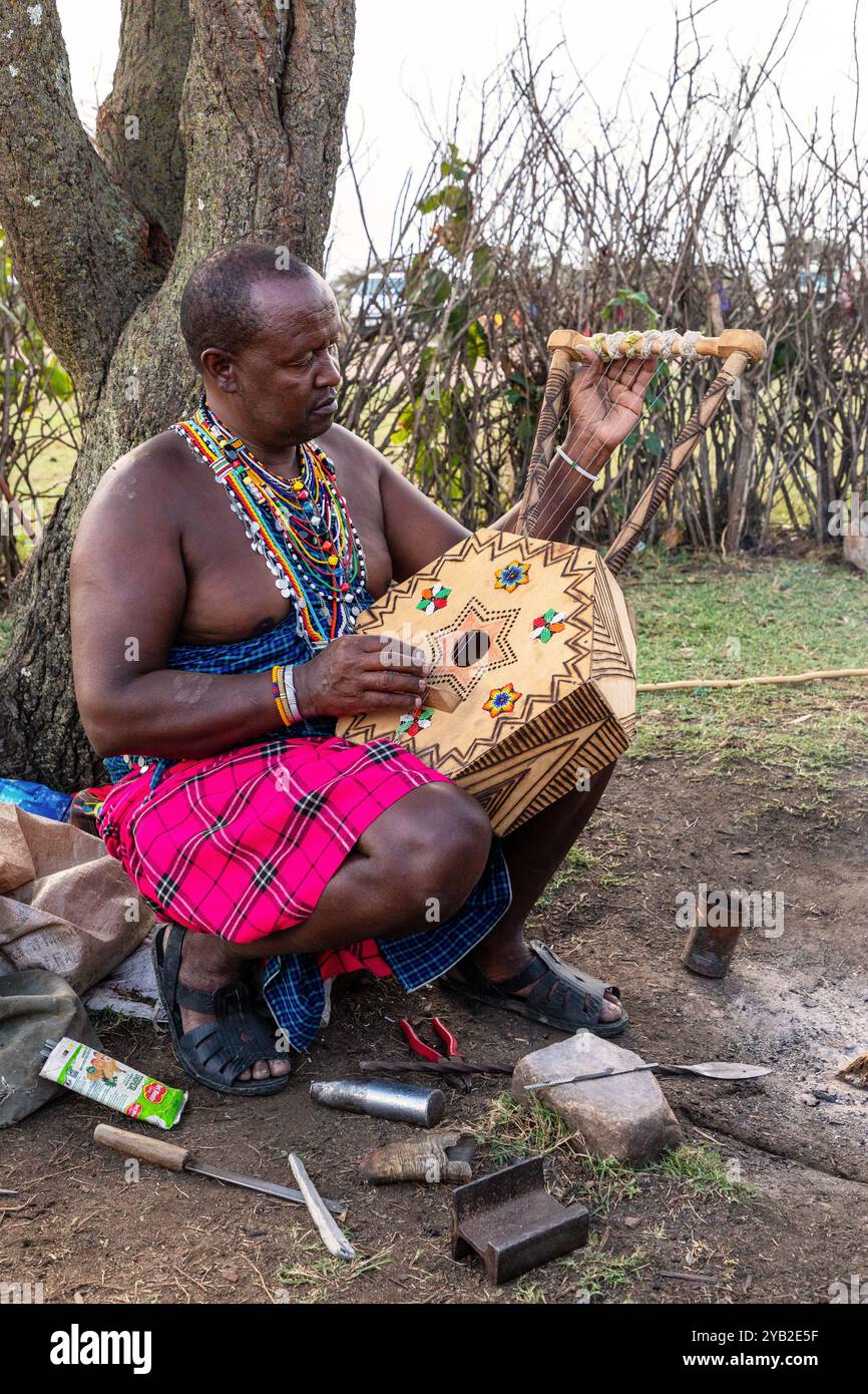 Masai man playing a traditional ornate litunga, Kenya stringed musical ...