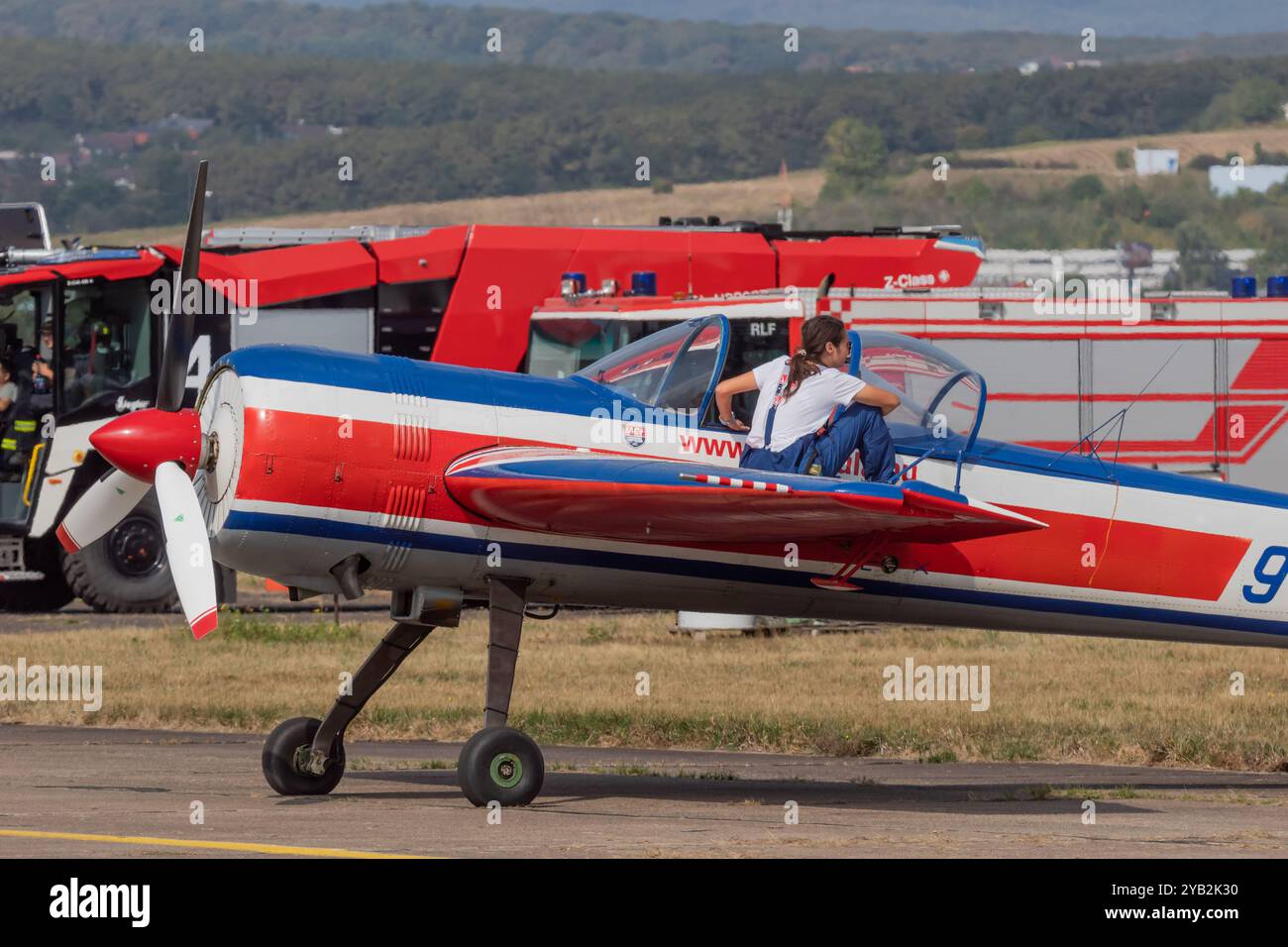 A woman sits on the wing of a Yakovlev Yak-55 aerobatic aircraft ...