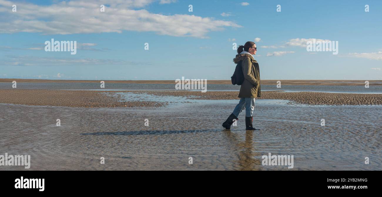 Woman in wellington boots walking on beach at low tide Stock Photo - Alamy