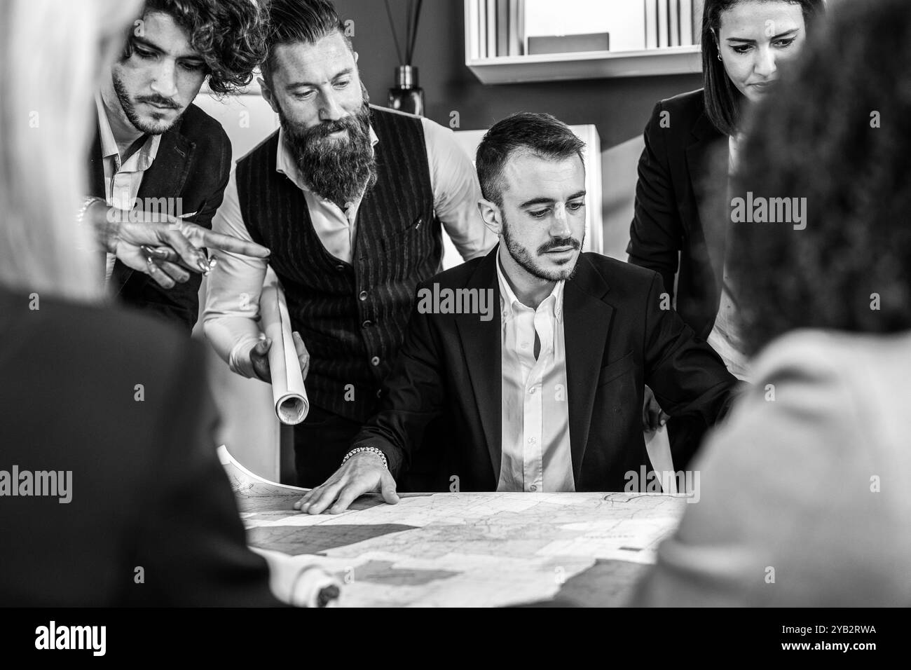 Focused business team analyzing plans during a meeting in a modern office. Professionals working ...