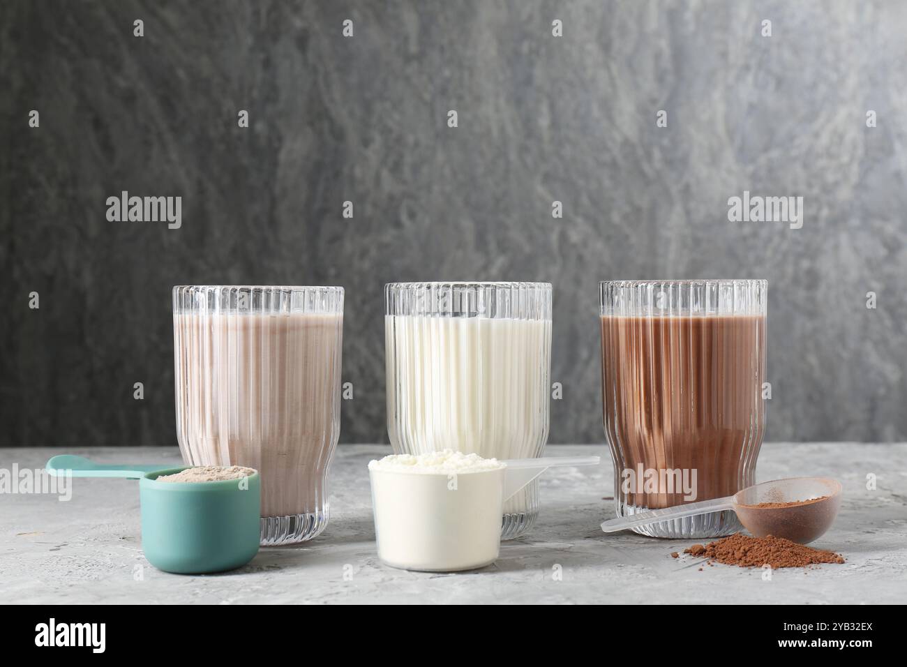 Delicious protein shakes in glasses and scoops with powder on gray ...