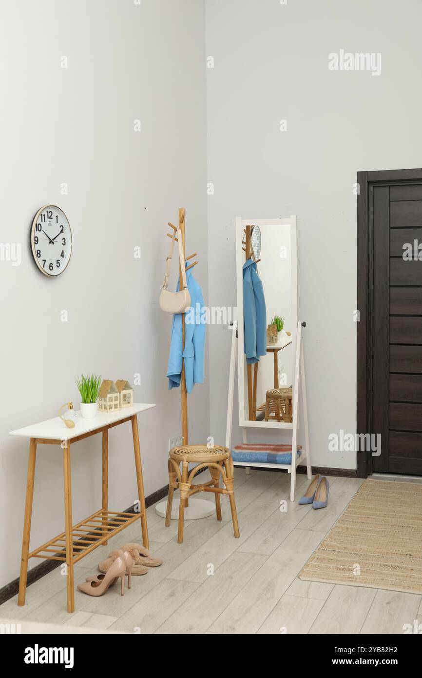 Clothing rack, mirror, storage bench and clothes in hallway Stock Photo ...