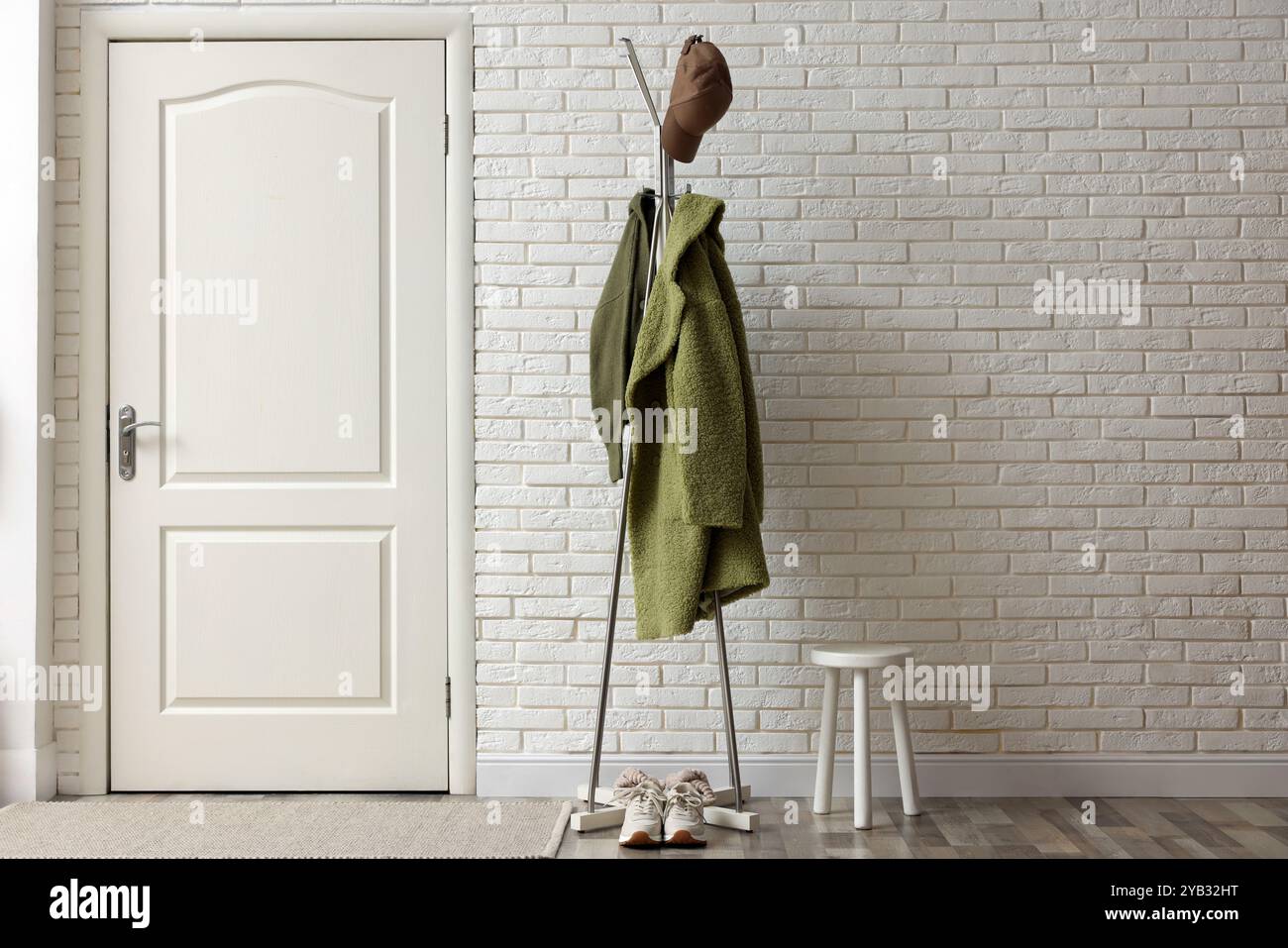 Metal rack with green coat and cap in hallway Stock Photo - Alamy