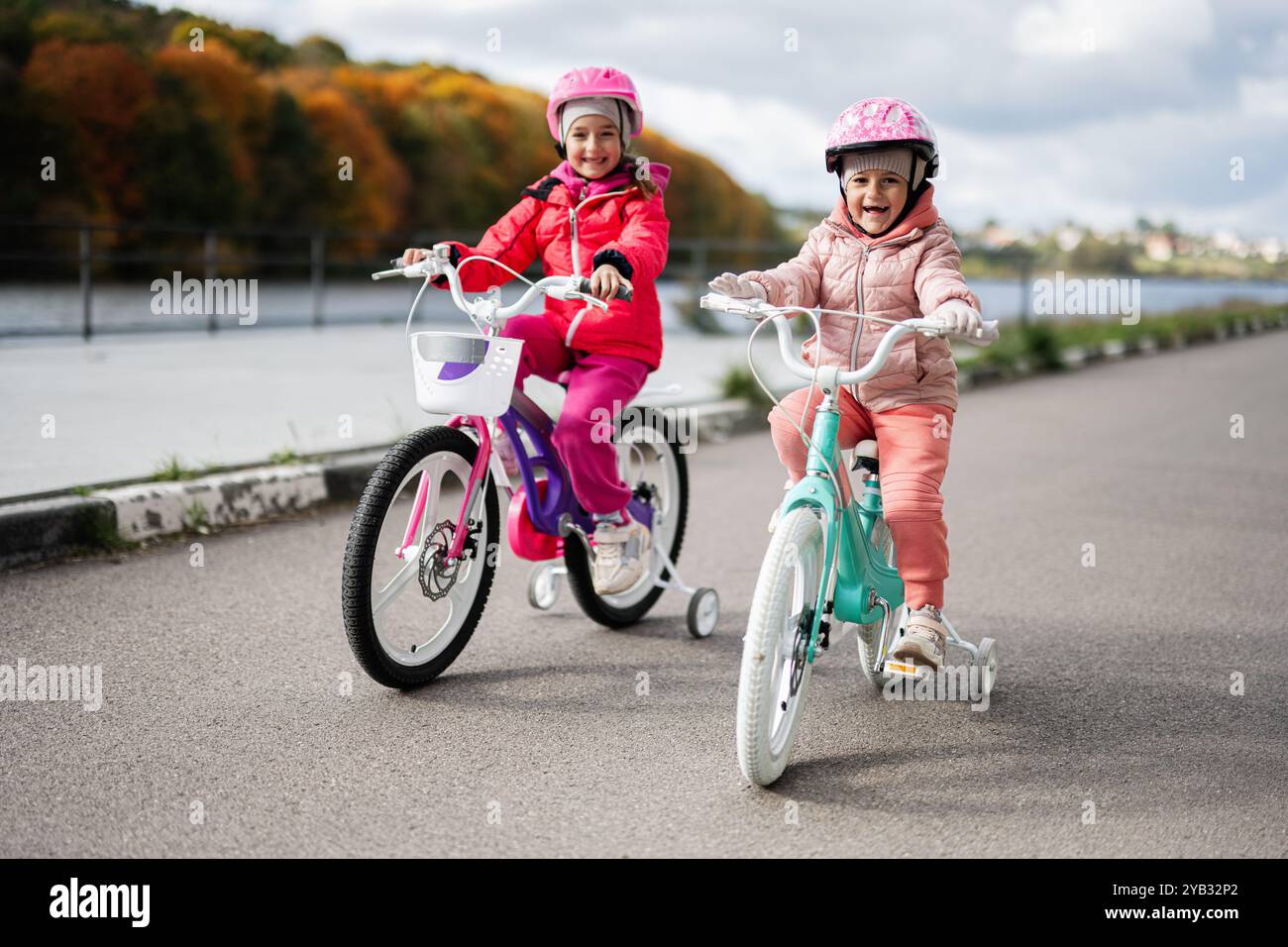 Two happy children wearing helmets ride their colorful bicycles on a ...