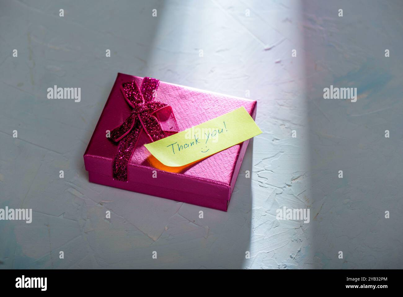 A pink gift box with a note saying Thank you on a soft background ...