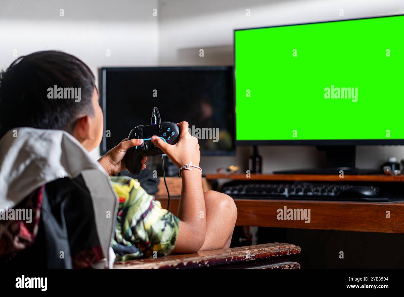 A person playing video games with a green screen monitor Stock Photo ...