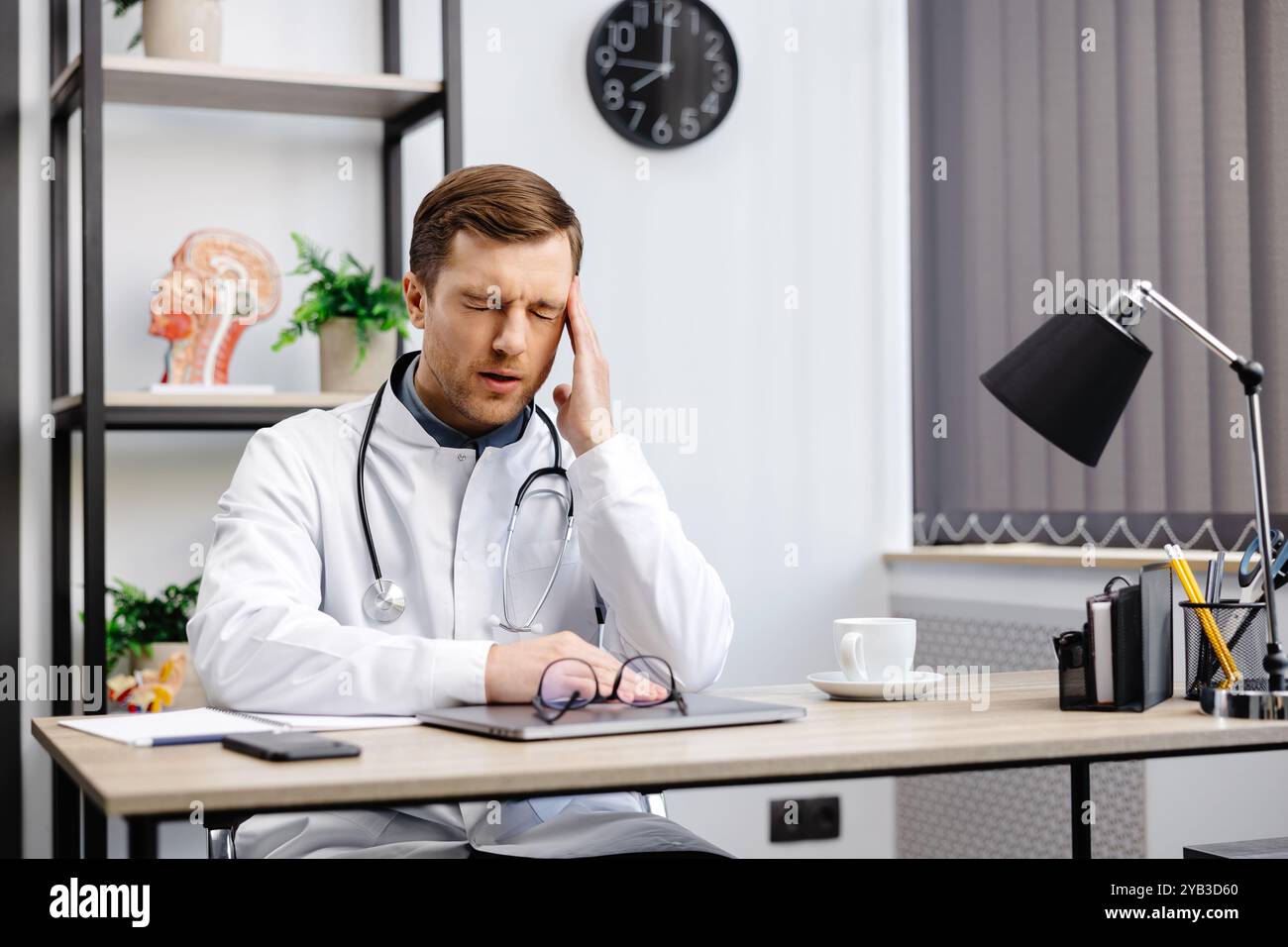 Handsome doctor man wearing medical uniform sitting on his workplace ...